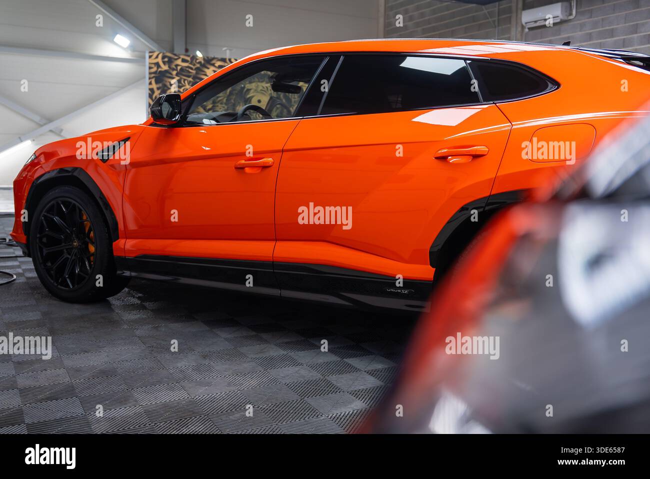 Orange Lamborghini Urus SE in modern workshop with black accents Stock ...