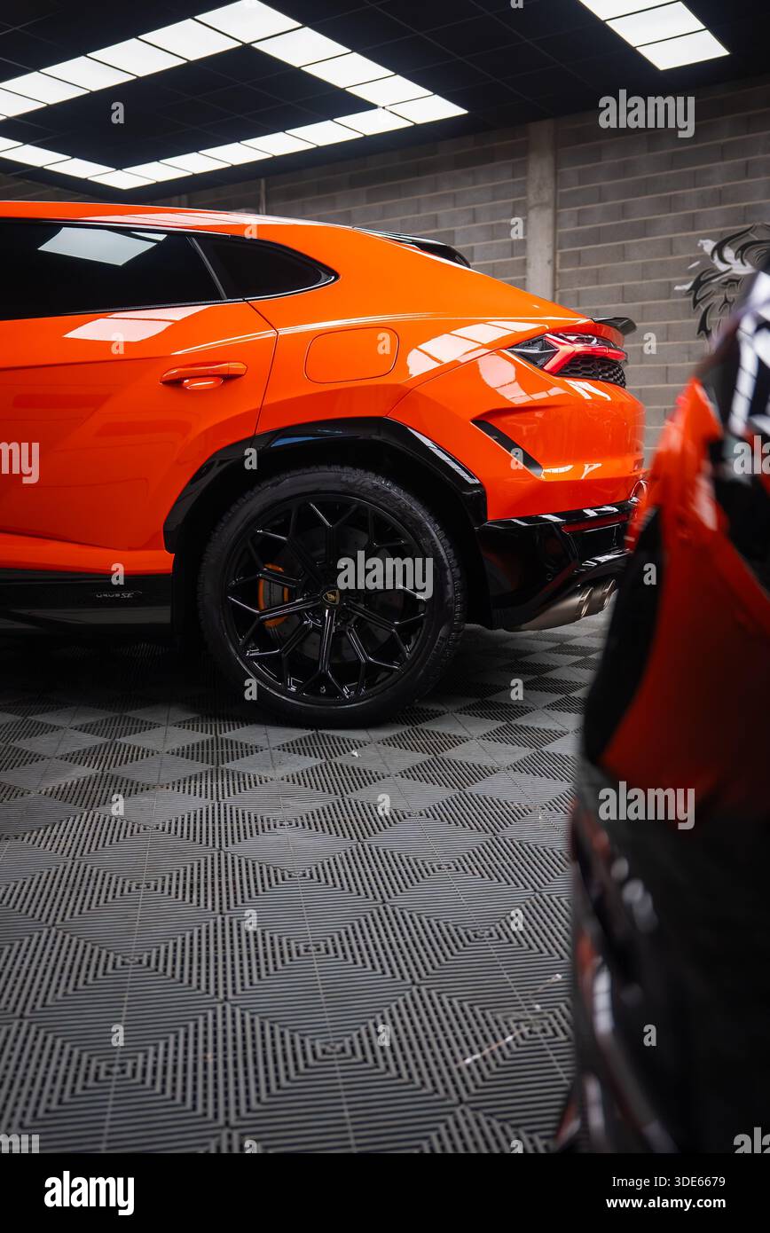 Orange Lamborghini Urus SE rear quarter in workshop with badge detail ...
