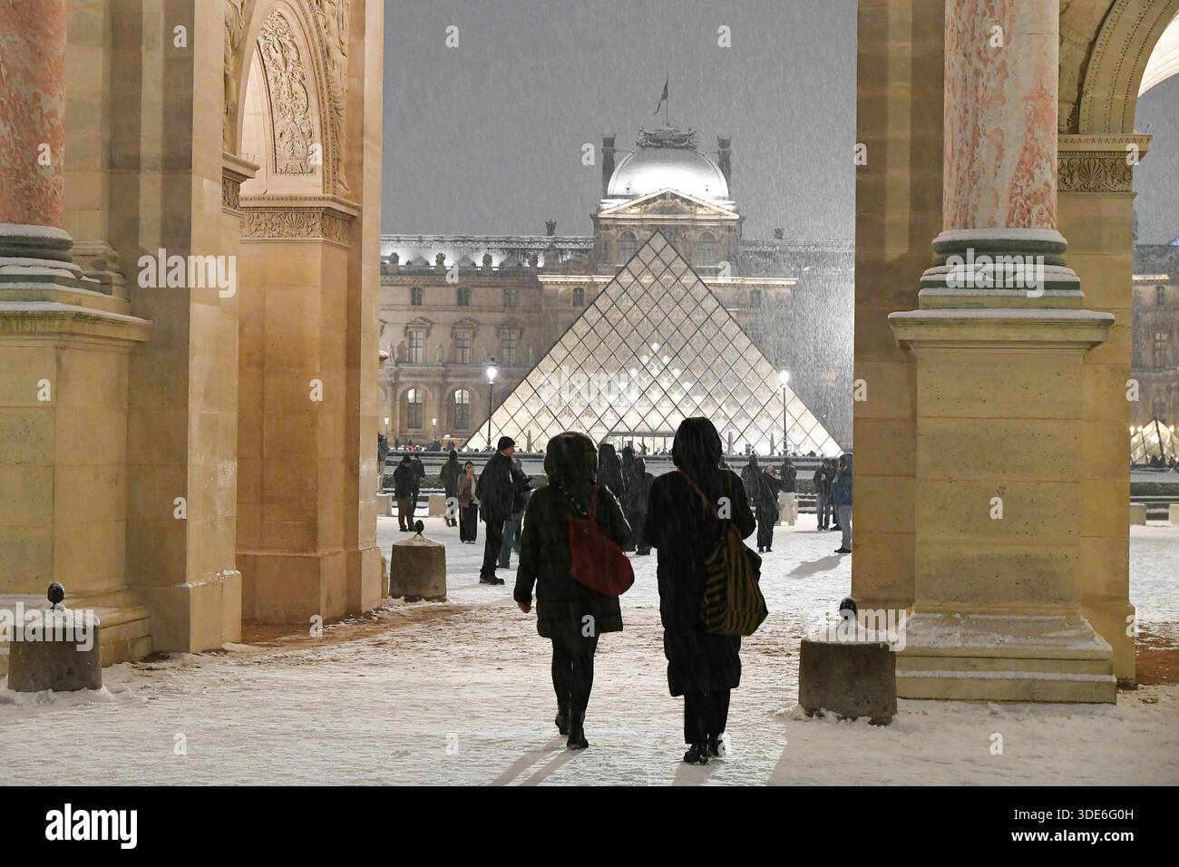People walk near the Louvre Museum after an intense snow episode, snow ...