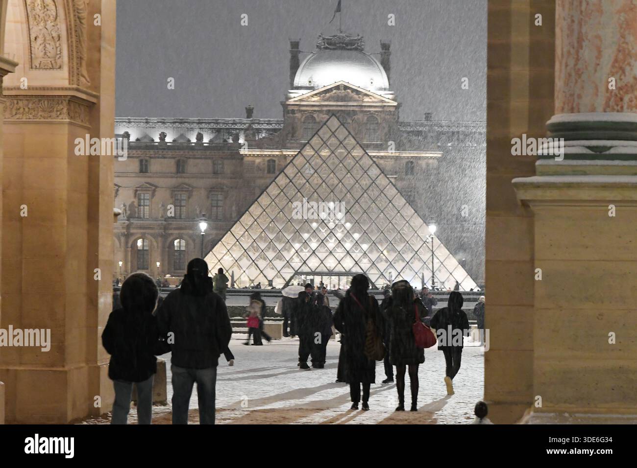 People walk near the Louvre Museum after an intense snow episode, snow ...