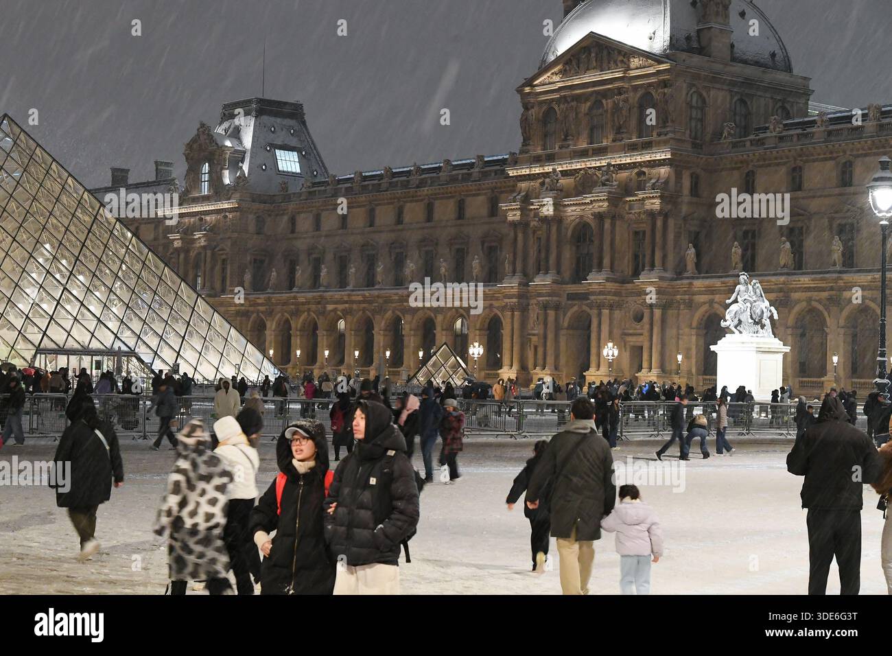 People walk near the Louvre Museum after an intense snow episode, snow ...