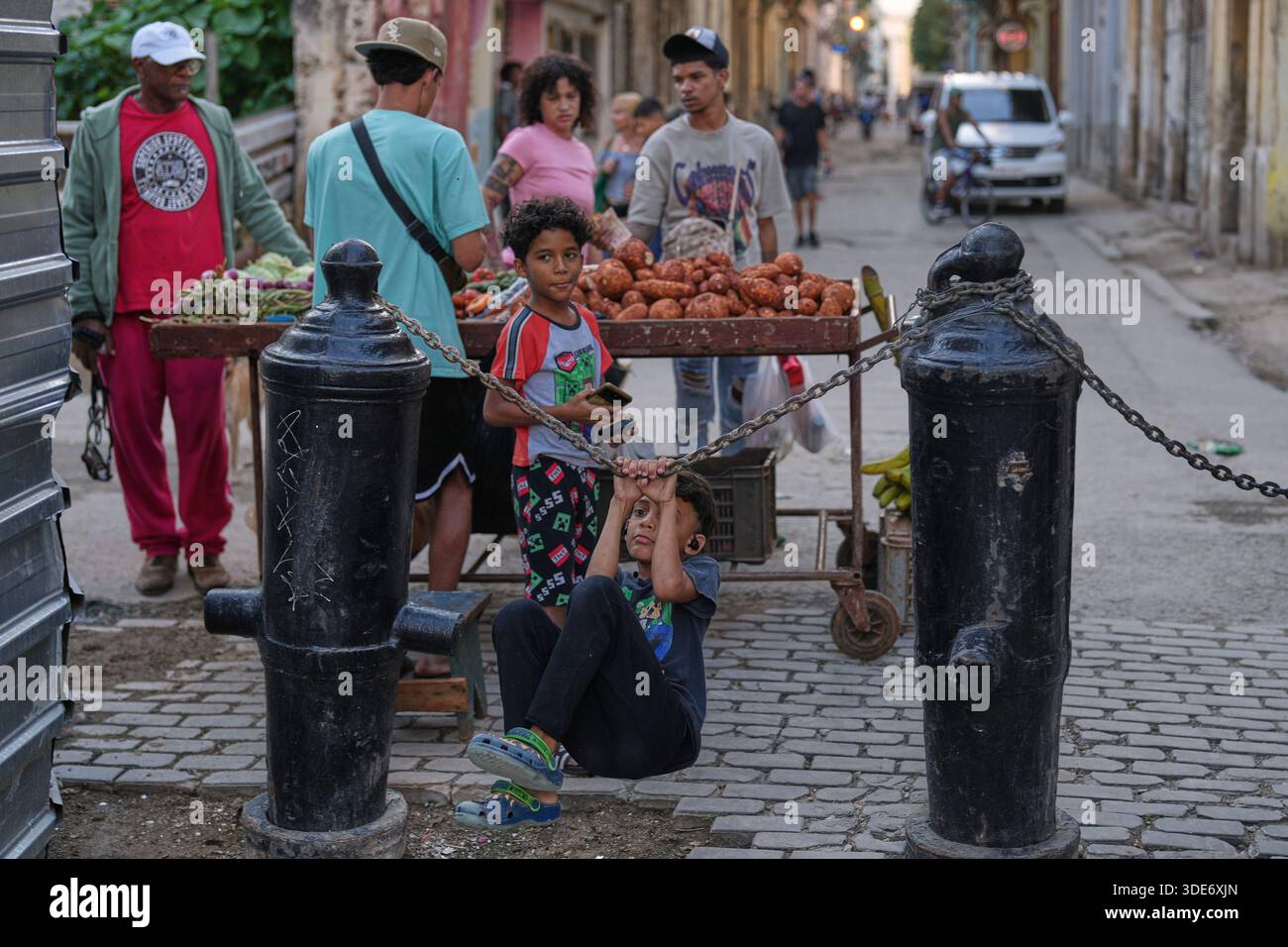 A child hangs on chains while customers shop at a street stall in Old ...