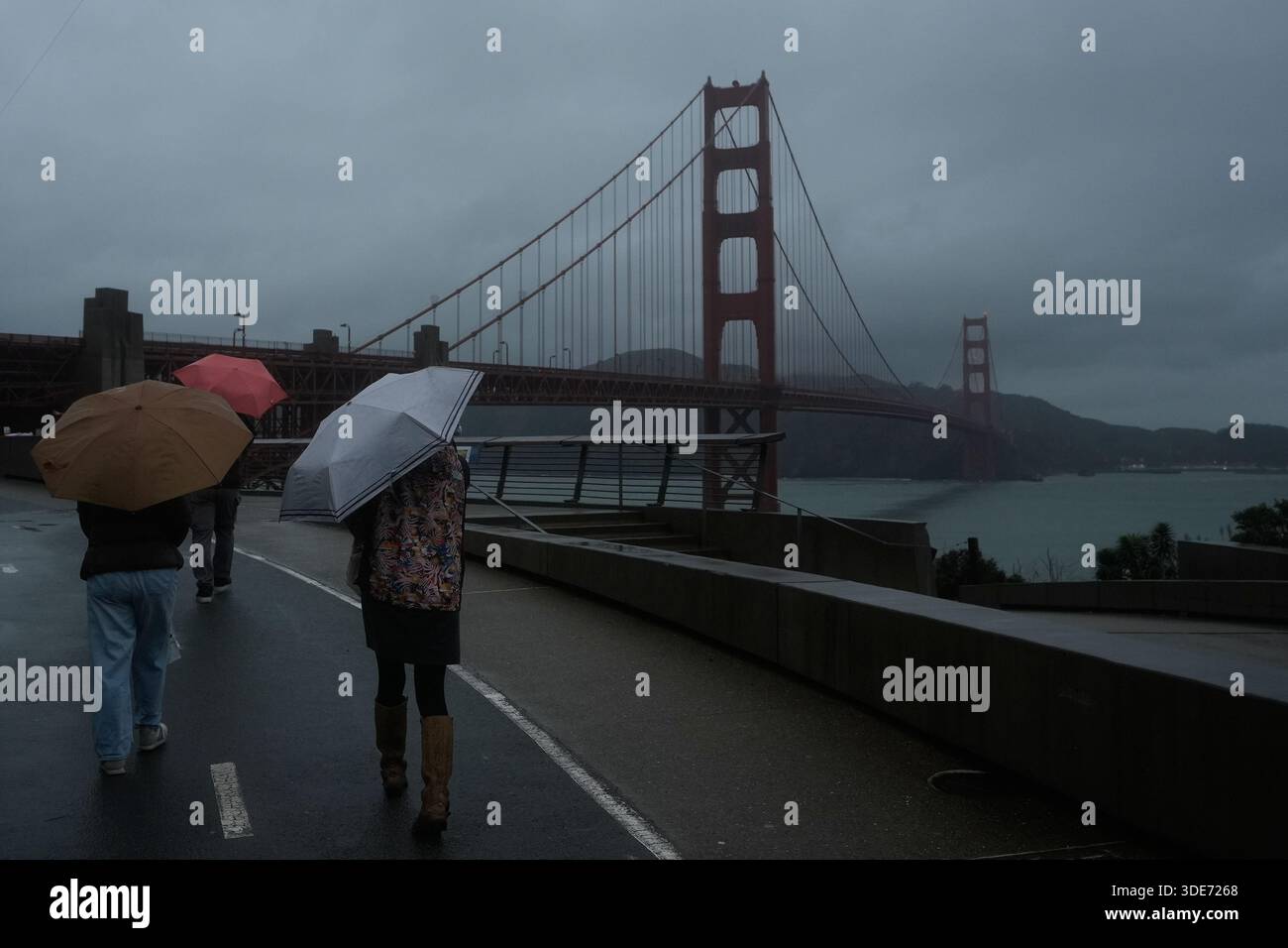 People carry umbrellas while walking on a path overlooking the Golden ...