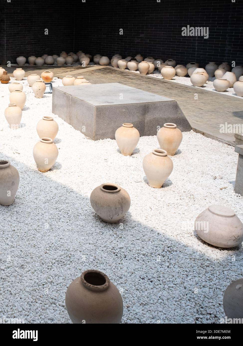 A collection of clay pottery jars and urns displayed on a bed of white ...