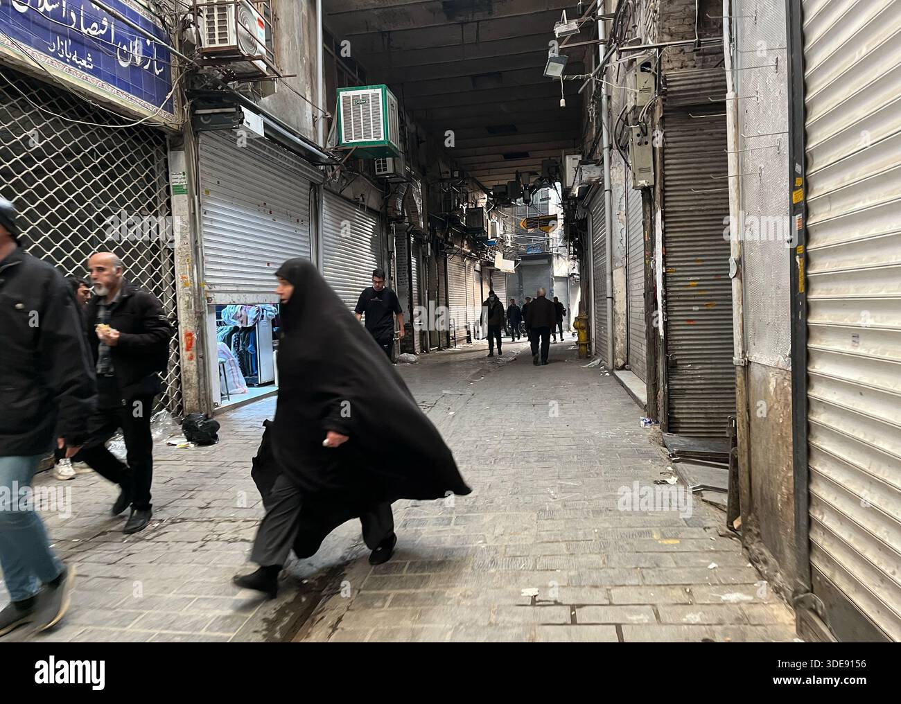 People walk as shops are closed during protests in Tehran's centuries ...