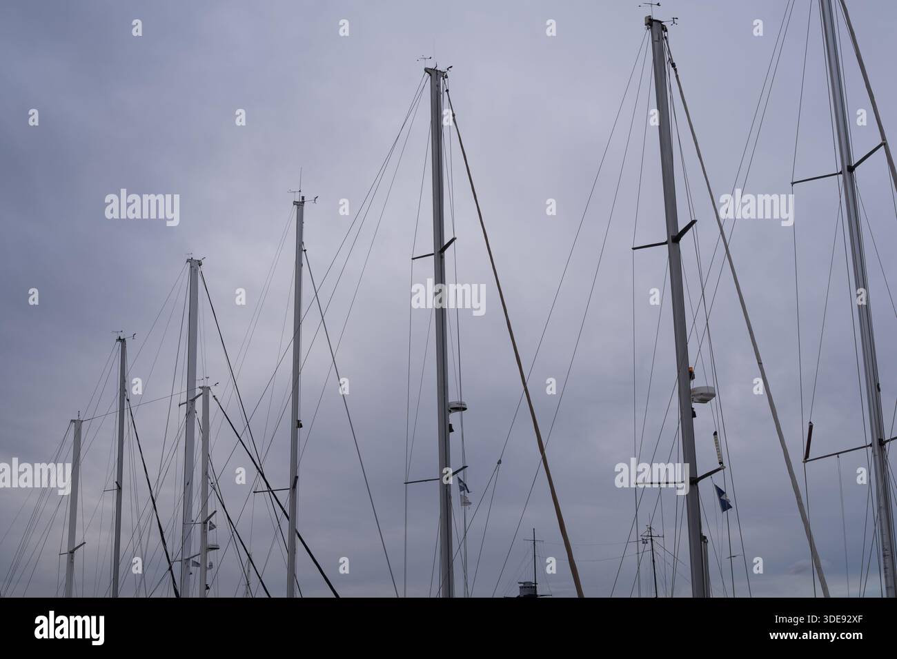 Sailboat masts and rigging in marina under cloudy sky. Nautical ...