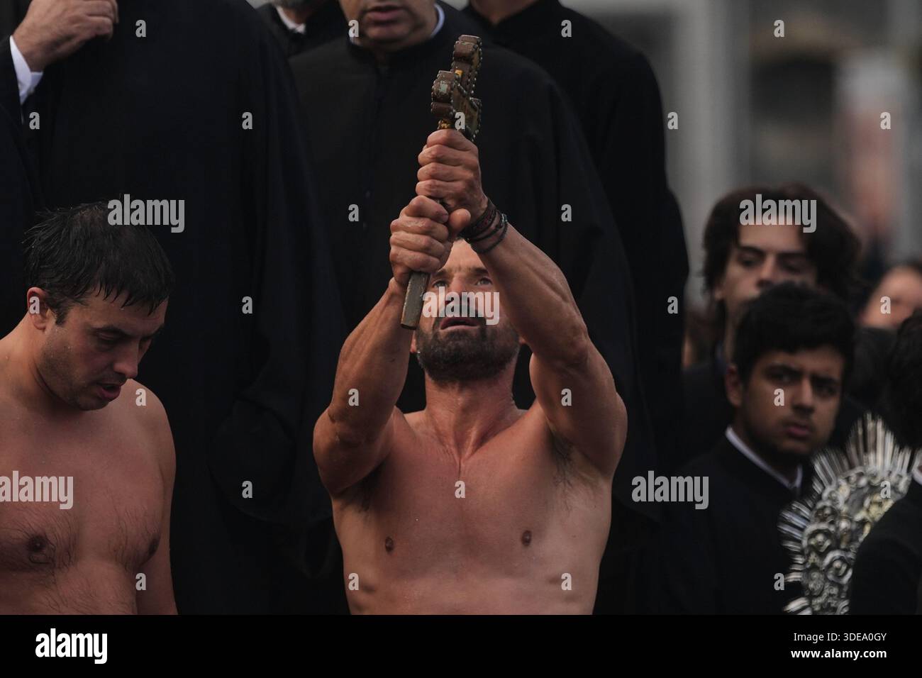 A Greek Orthodox faithful holds up a wooden cross after being retrieved ...