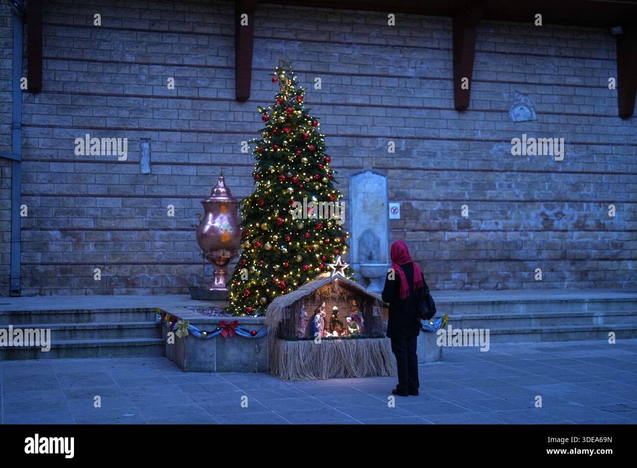 A Orthodox Christian faithful stands in front of a Christmas tree and a ...