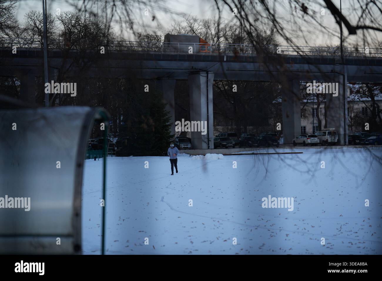 A man is seen exercising on a snow covered running track in Warsaw ...