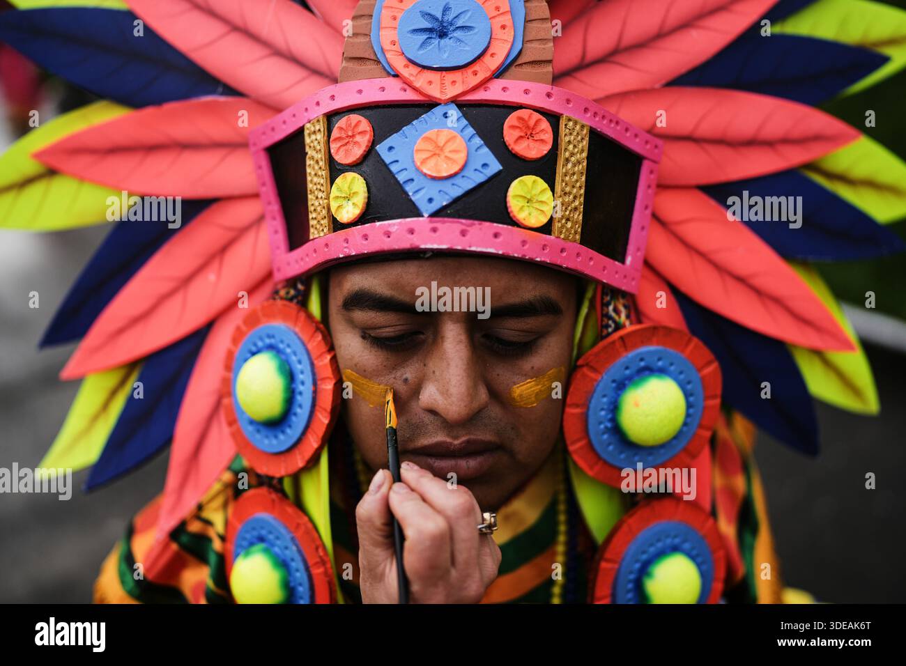 A reveler prepares for the Black and White Carnival, recognized by ...