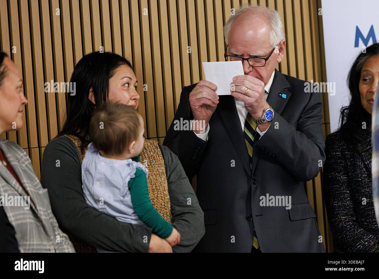 Gov. Tim Walz smiles at a child before speaking during a press ...