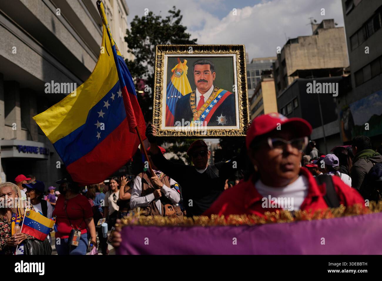A government supporter holds an image of President Nicolas Maduro ...