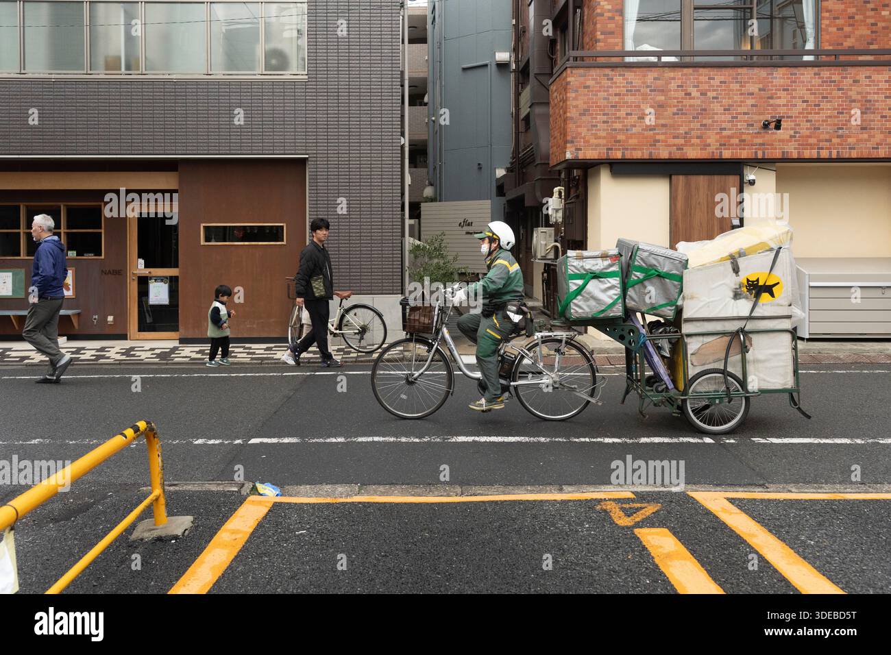 A delivery person cycles through Fudo Dori Shibuya, Tokyo, delivering ...