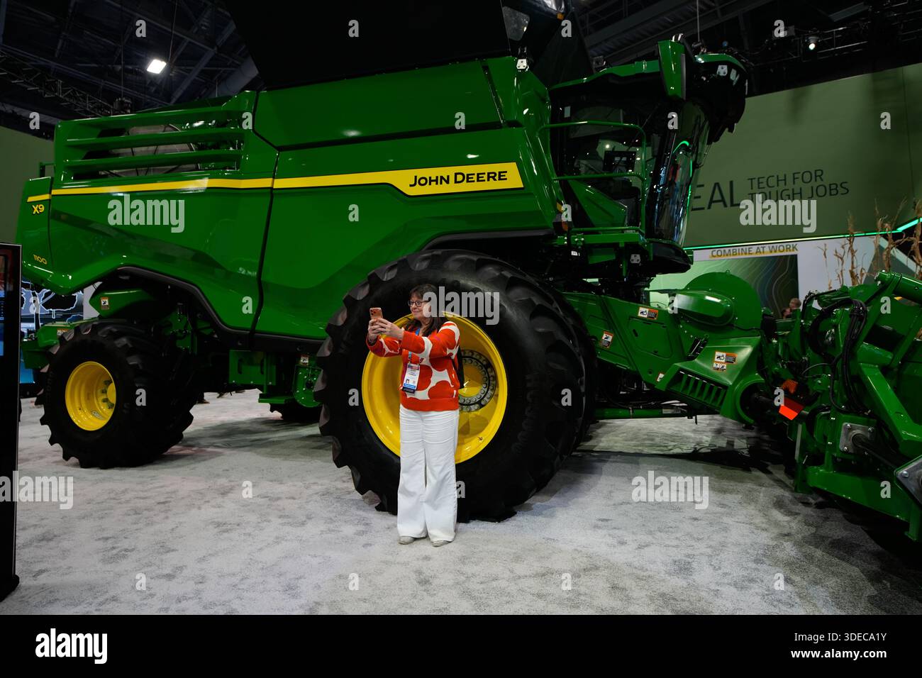 A person takes a picture in front of the X9 1100 combine at the John ...