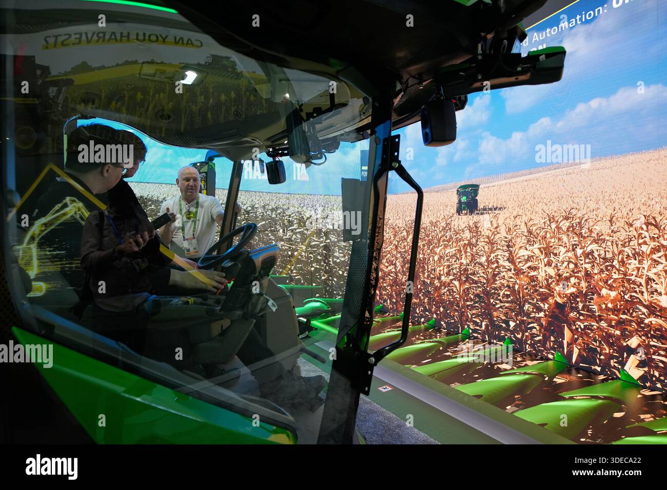 A man instructs others at a combine simulator at the John Deere booth ...