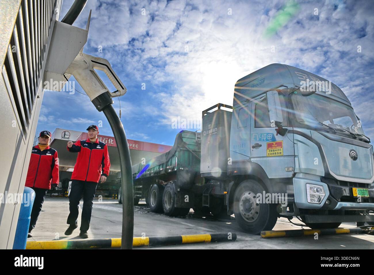 Employees provide charging services for heavy-duty trucks at a charging ...