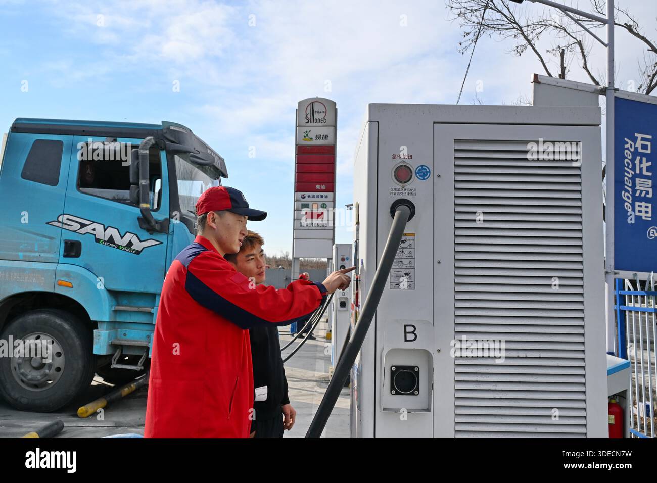 Employees provide charging services for heavy-duty trucks at a charging ...