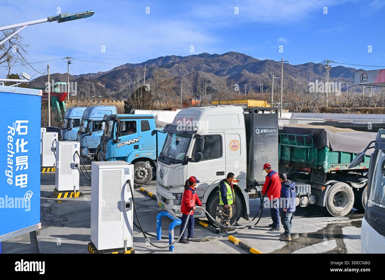 Employees provide charging services for heavy-duty trucks at a charging ...