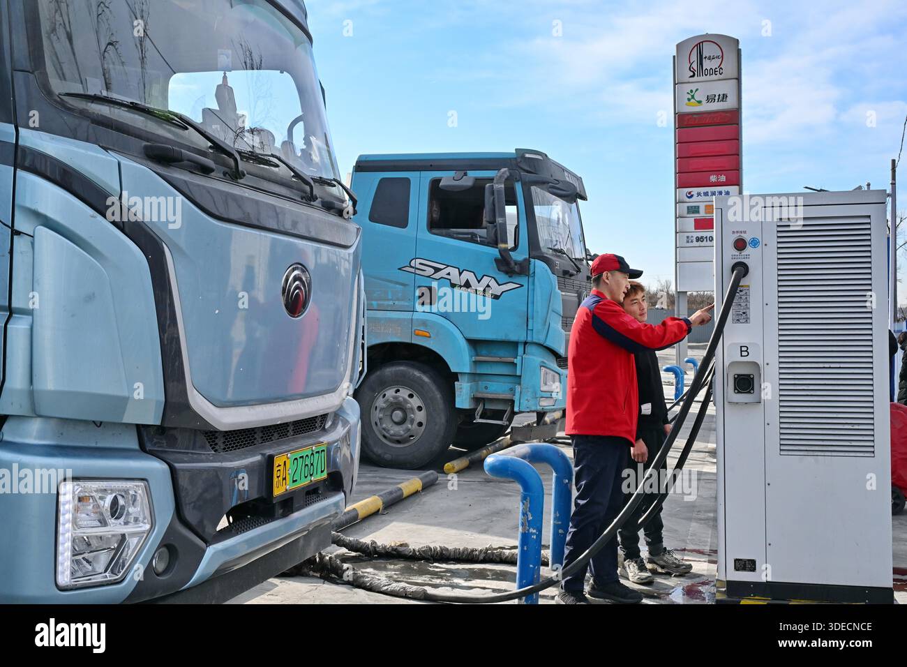 Employees provide charging services for heavy-duty trucks at a charging ...