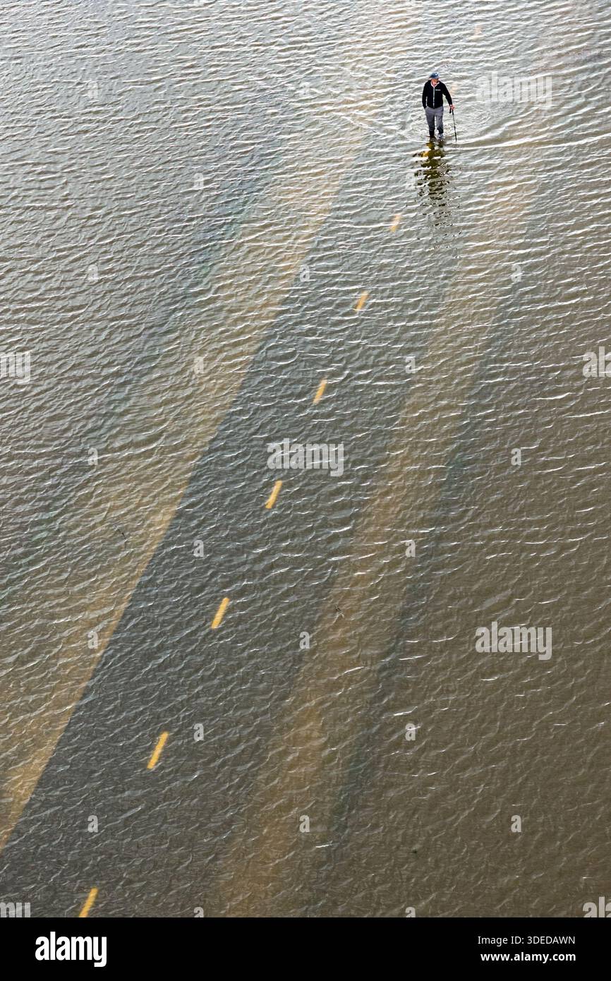FILE - A person runs along a flooded path caused by the king tides in ...