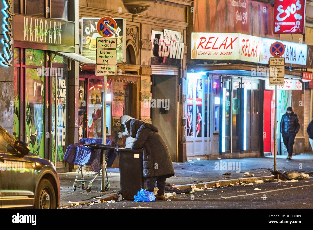 A person looks for food in a trash bin in the red light district in ...