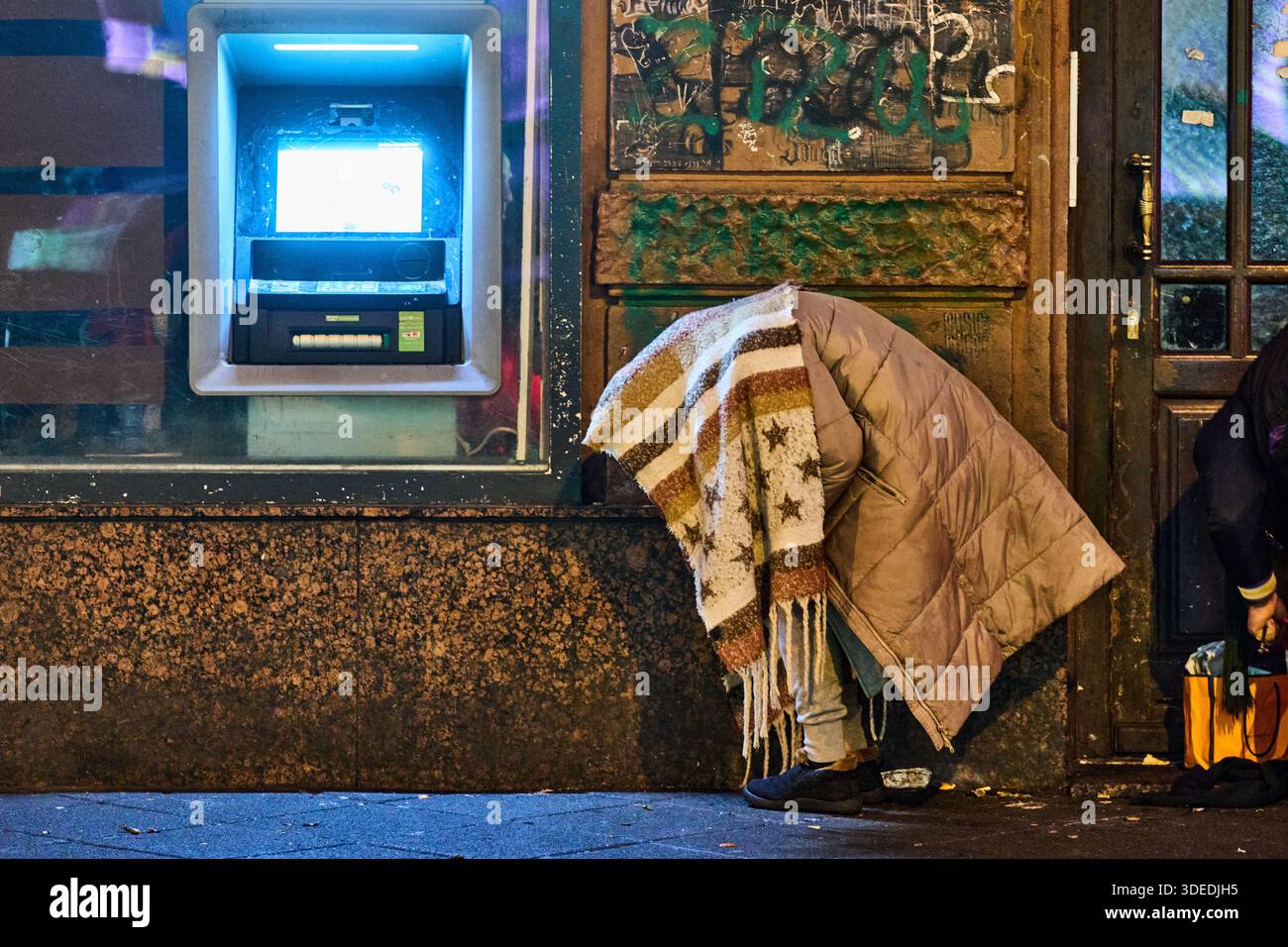 A woman covers herself with a blanket against the cold temperature next ...