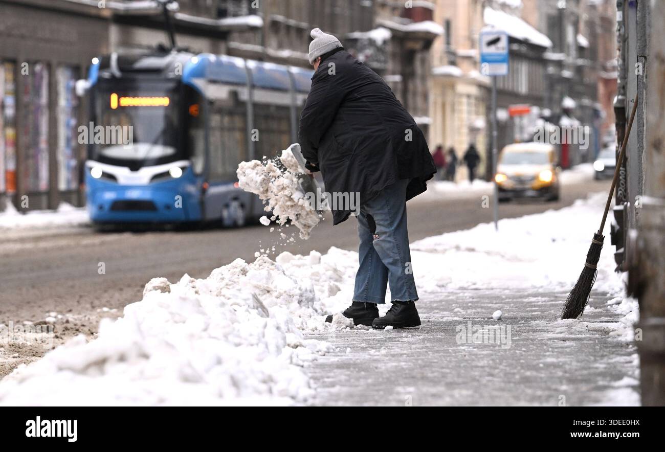 Man clears snow from a street in Zagreb, Croatia, on January 7, 2026 ...