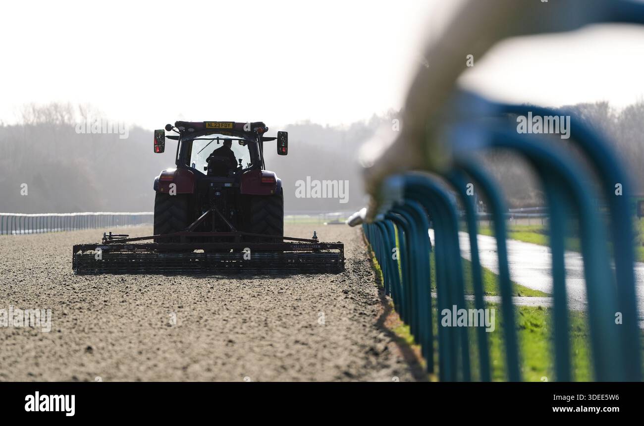 A tractor levels the track ahead of racing at Lingfield Park racecourse ...