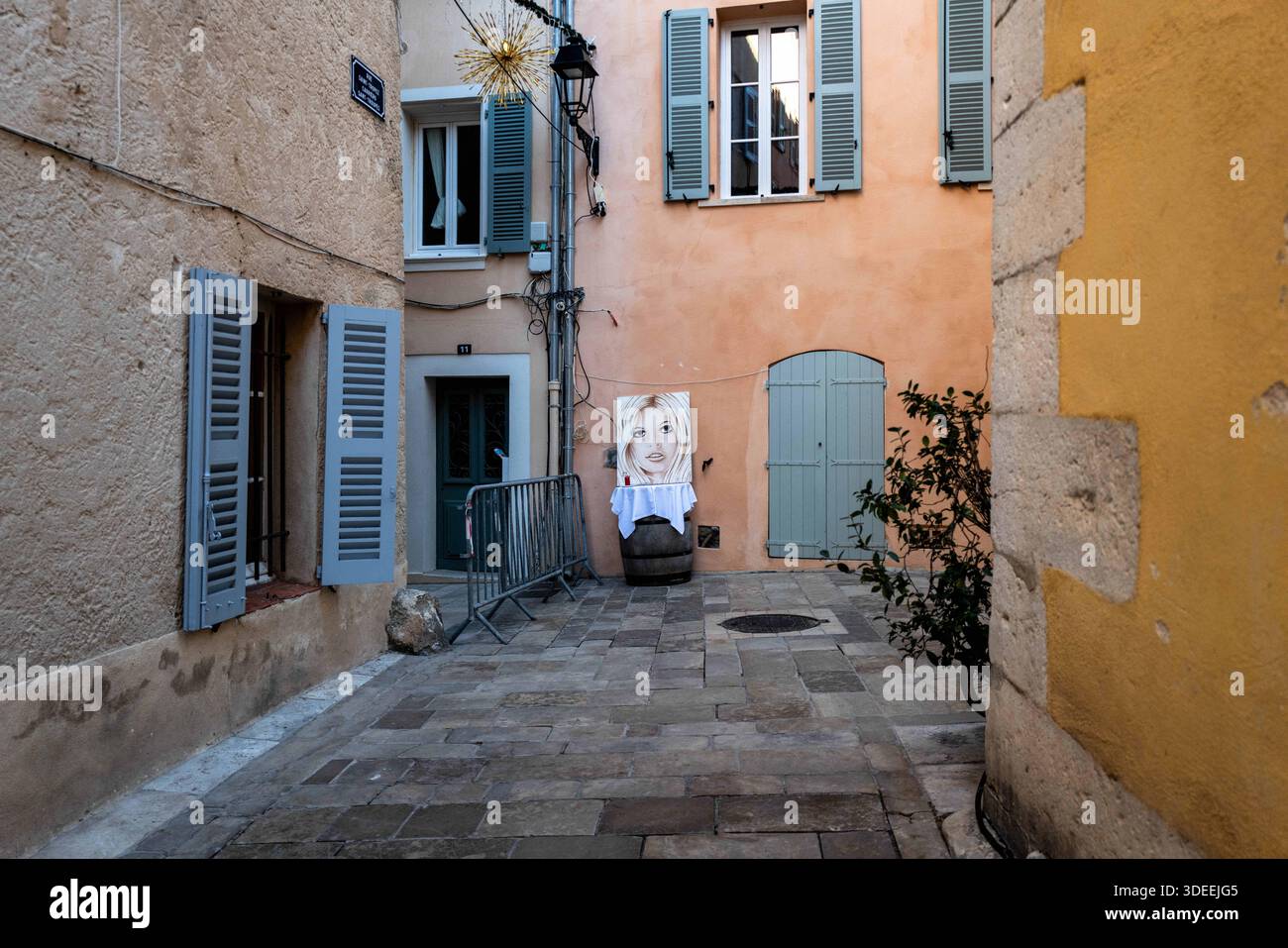 A painted portrait of Brigitte Bardot and a candle seen in an alleyway ...