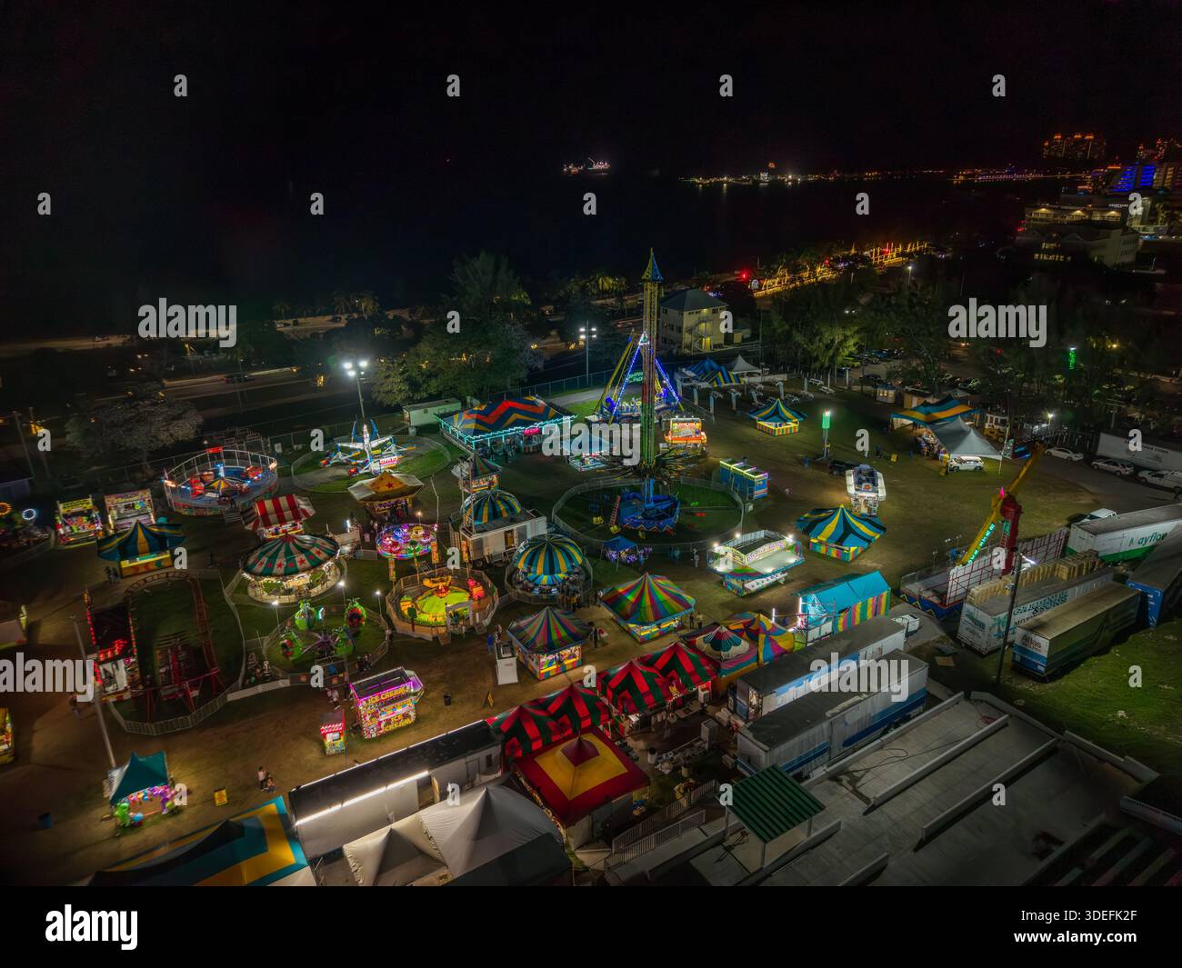 Aerial view of a brightly lit carnival ground with spinning rides and ...