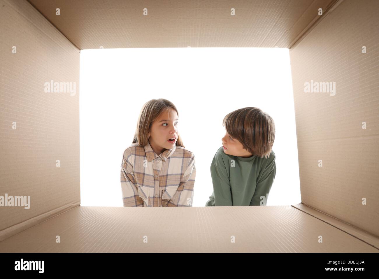 Excited kids looking into cardboard box on white background, view from ...