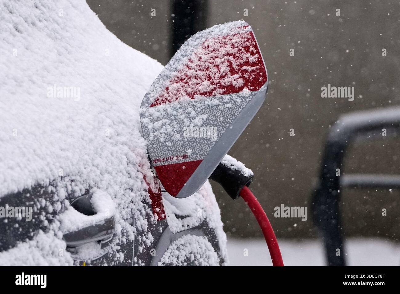 An electric car is charged during a cold winter day in the snow in ...