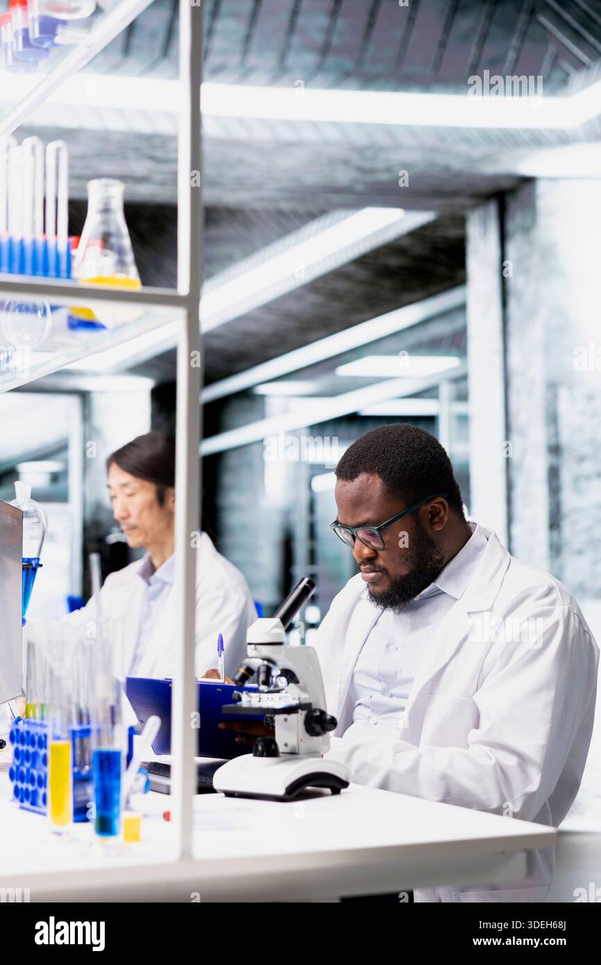 Clinical microbiologist operating compound microscope does detailed ...