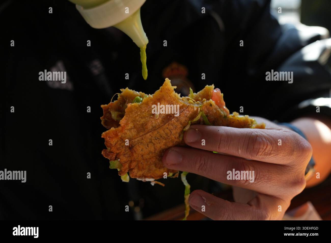 A Venezuelan migrant eats a "patacón," a typical Venezuelan dish, at ...