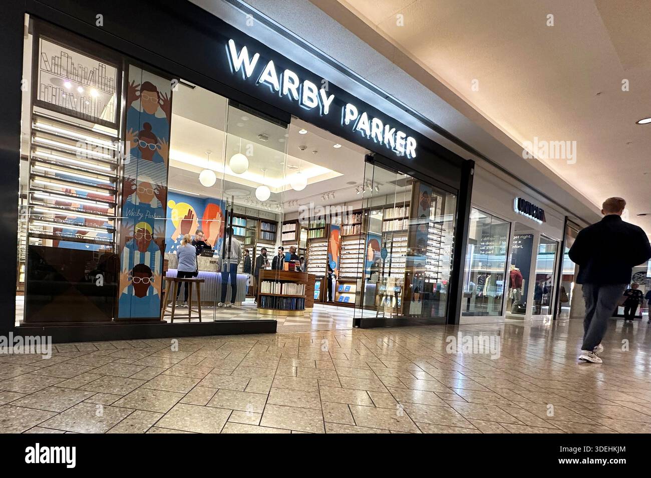 A lone shopper passes a Warby Parker store in Cherry Creek Mall ...