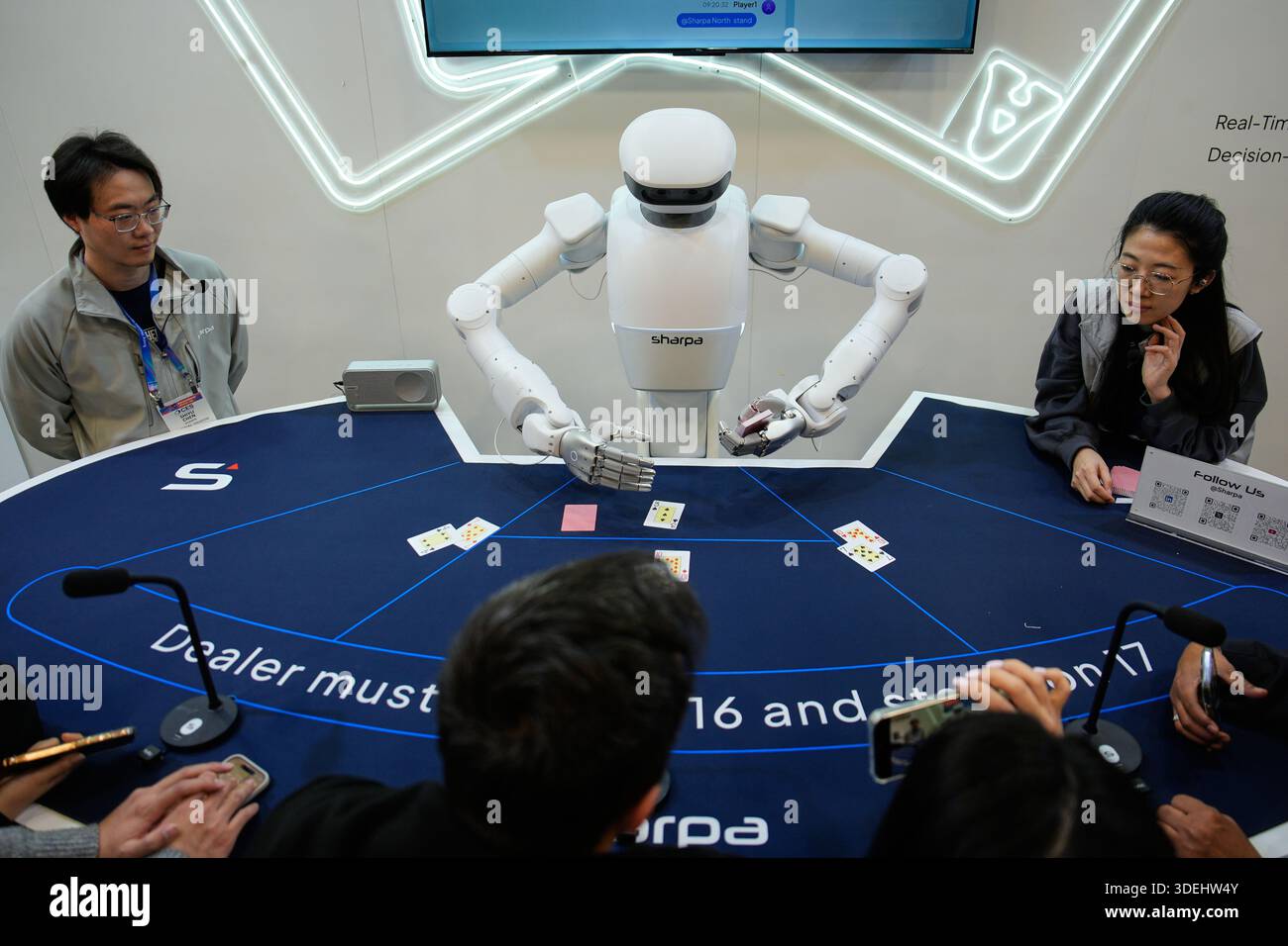 People watch as the Sharpa North robot deals poker at the Sharpa booth ...