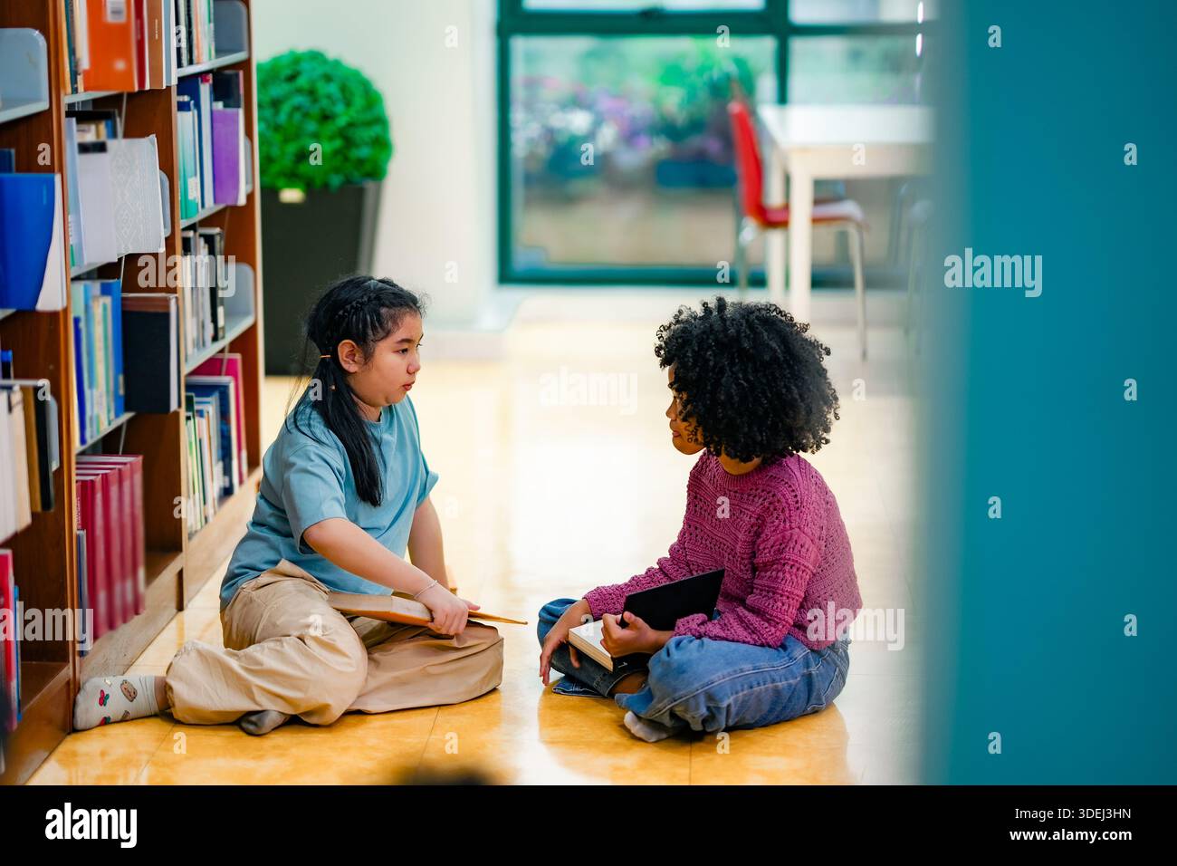 Children engaged in reading session on library floor near bookshelves ...