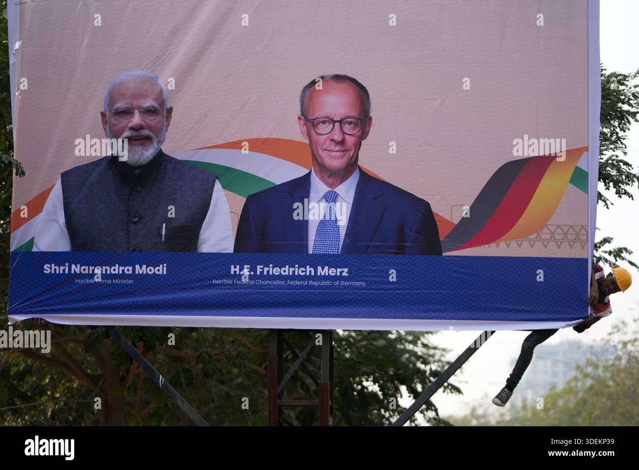 A worker installs a hoarding welcoming German Chancellor Friedrich Merz ...
