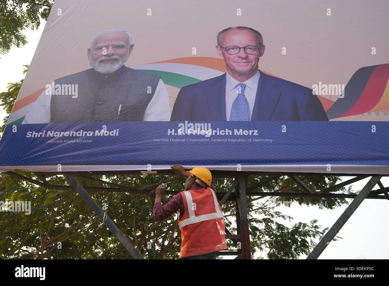 A worker installs a hoarding welcoming German Chancellor Friedrich Merz ...
