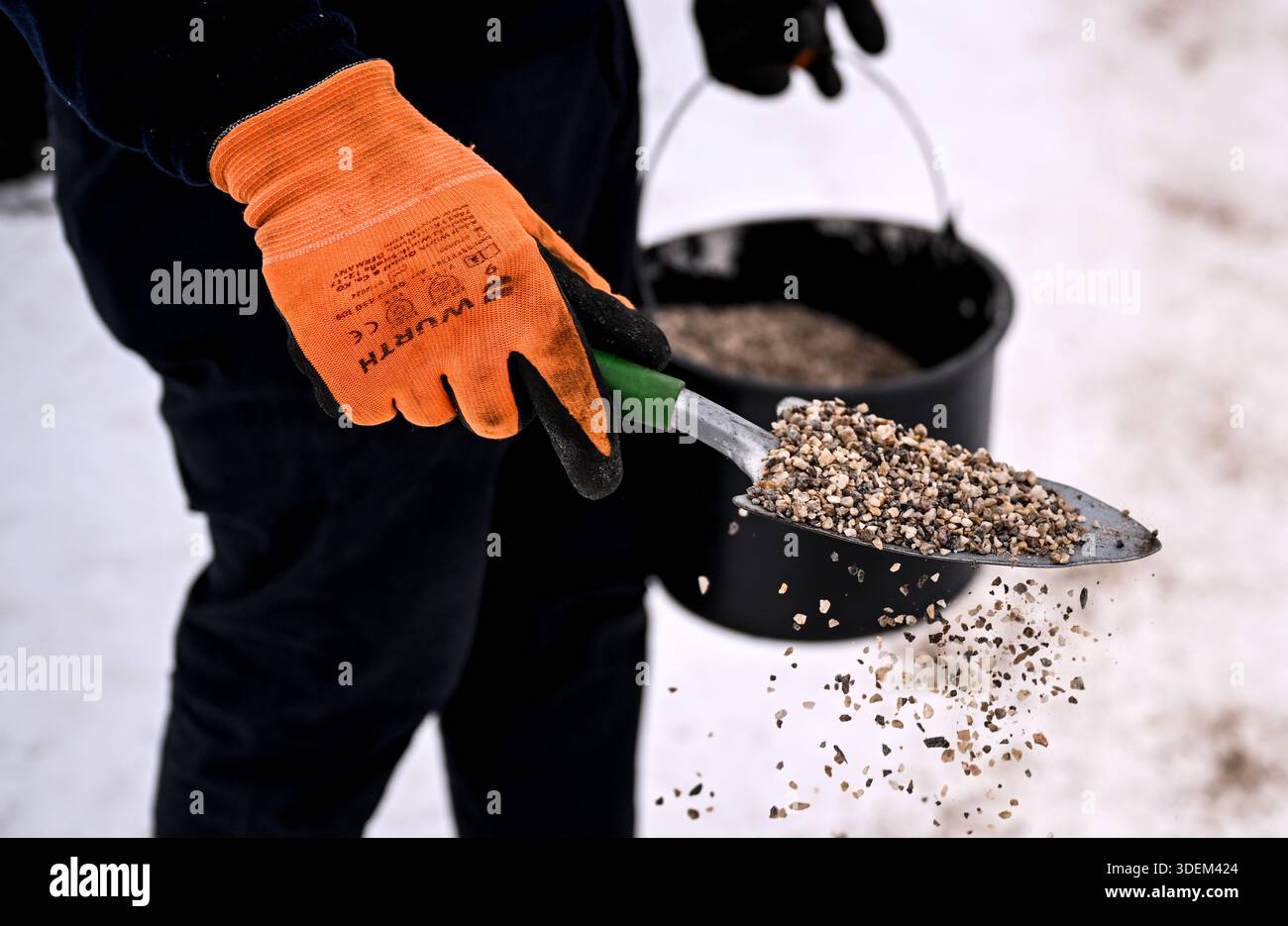 08 January 2026, Berlin: A young man is gritting the sidewalk in front ...