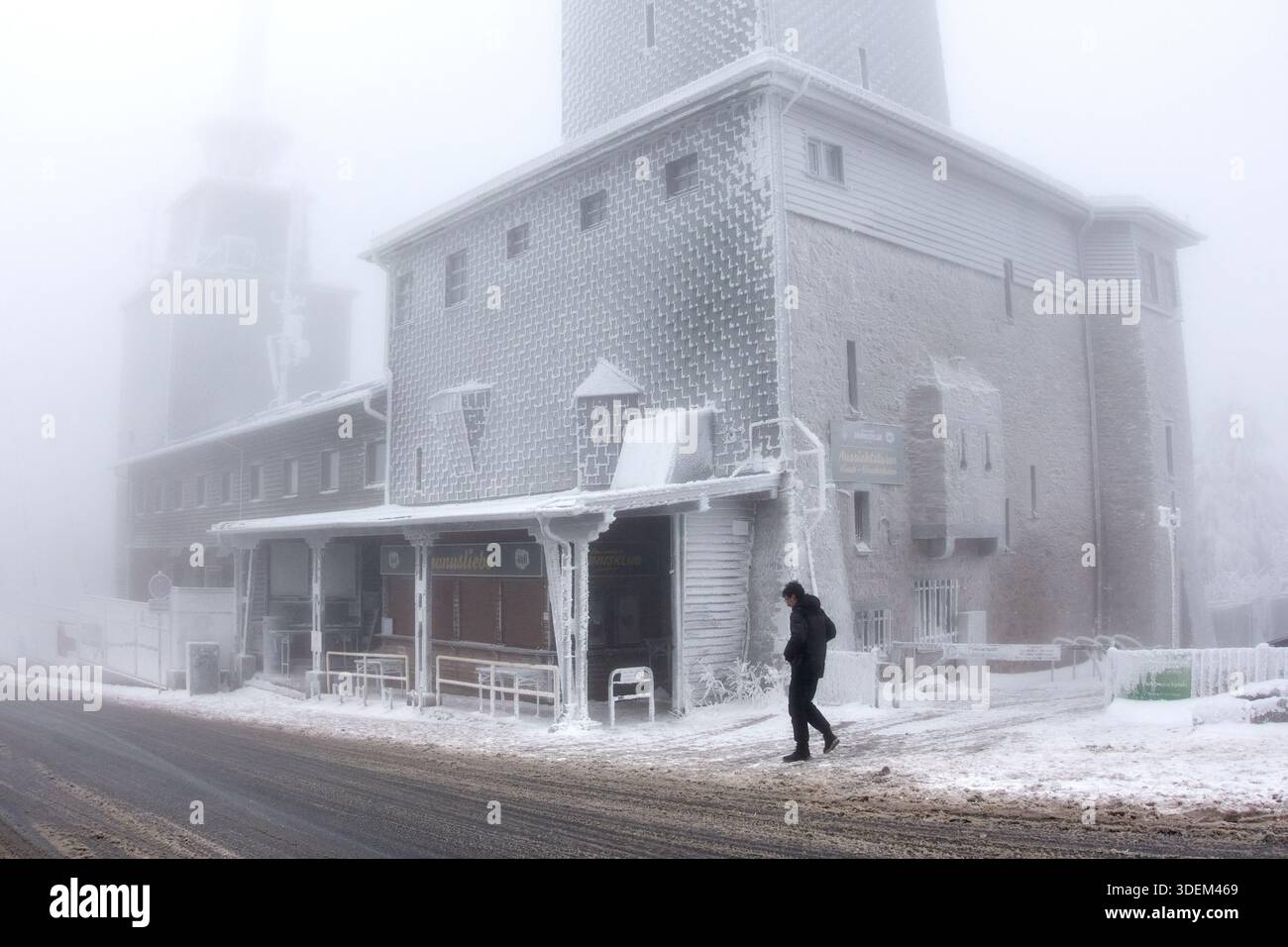 A man walks past an ice covered building on top of the Feldberg ...