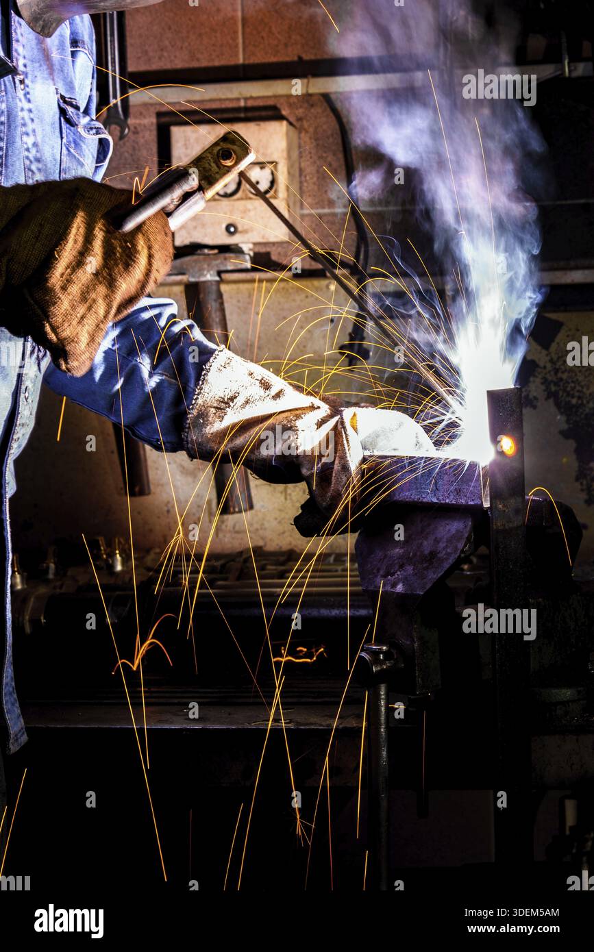 Welder at work welding steel structures in the workshop in production ...