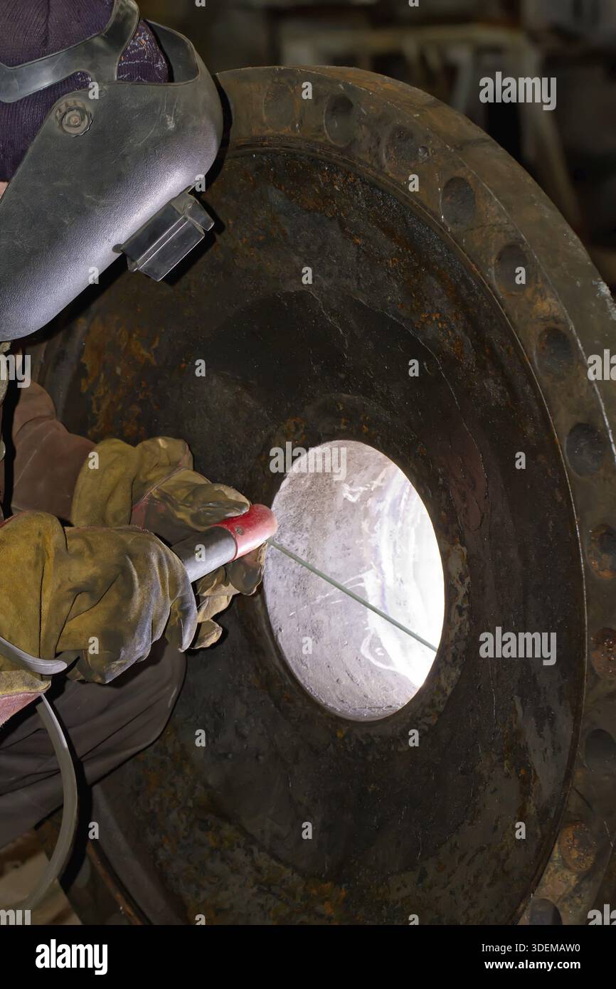 Welder is repairing the defective area of the weld inside the parts of ...