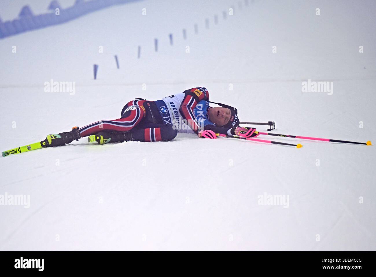 Martin Uldal from Norway lies on the snow after completing the Biathlon ...