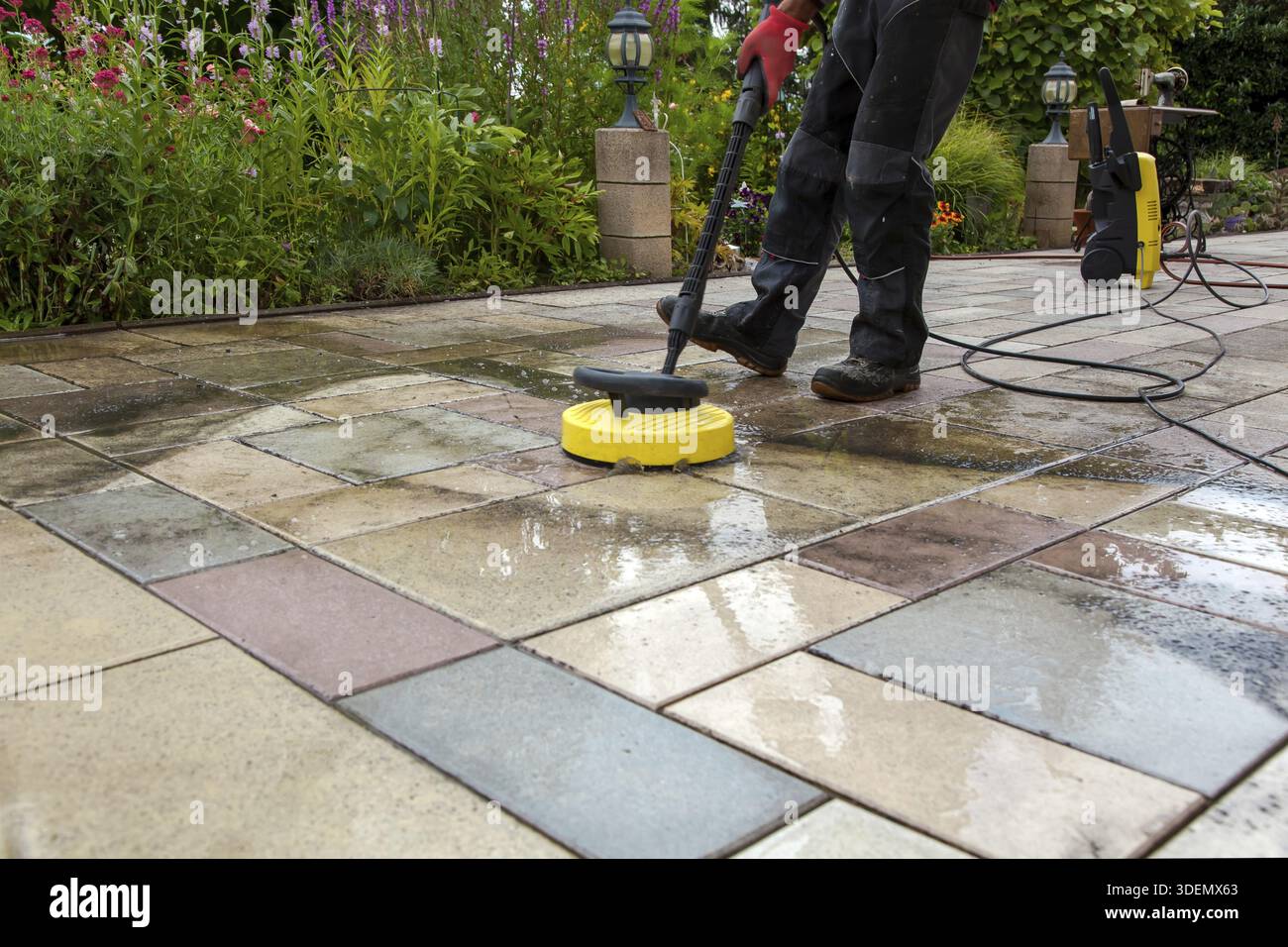 Cleaning stone slabs on patio with the high-pressure cleaner. Person ...