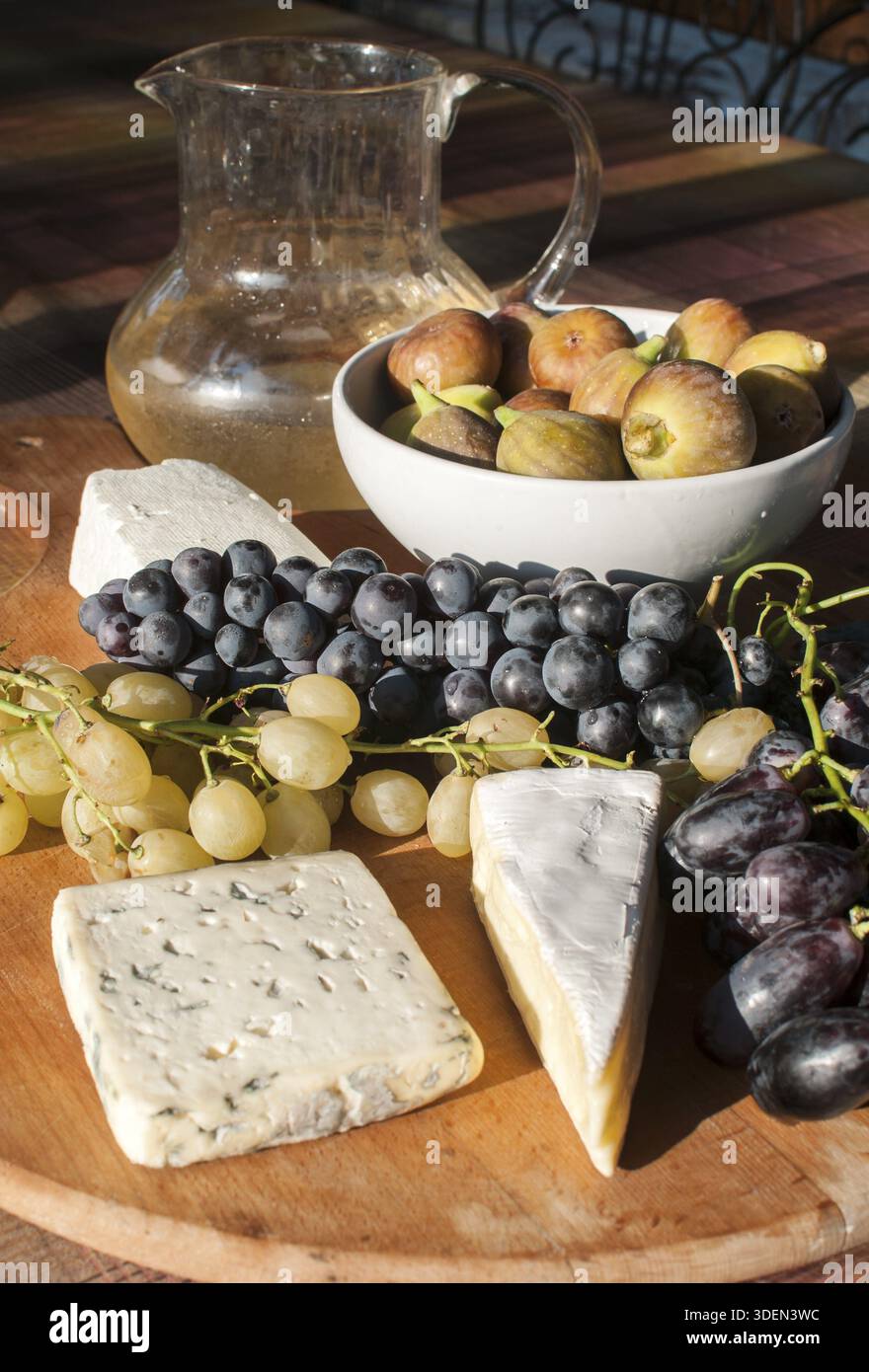 Wooden plateau with fresh grapes figs and types of cheese closeup as ...