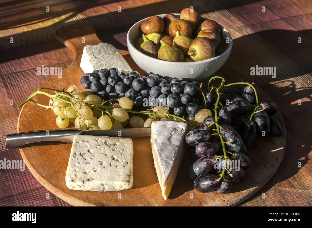 Wooden plateau with fresh grapes figs and types of cheese closeup as ...