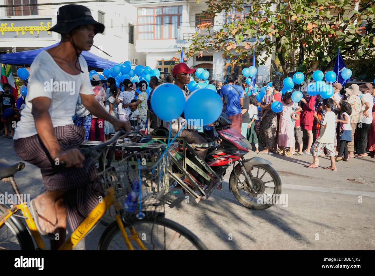 Vehicles make their ways while people gather at an election campaign by ...