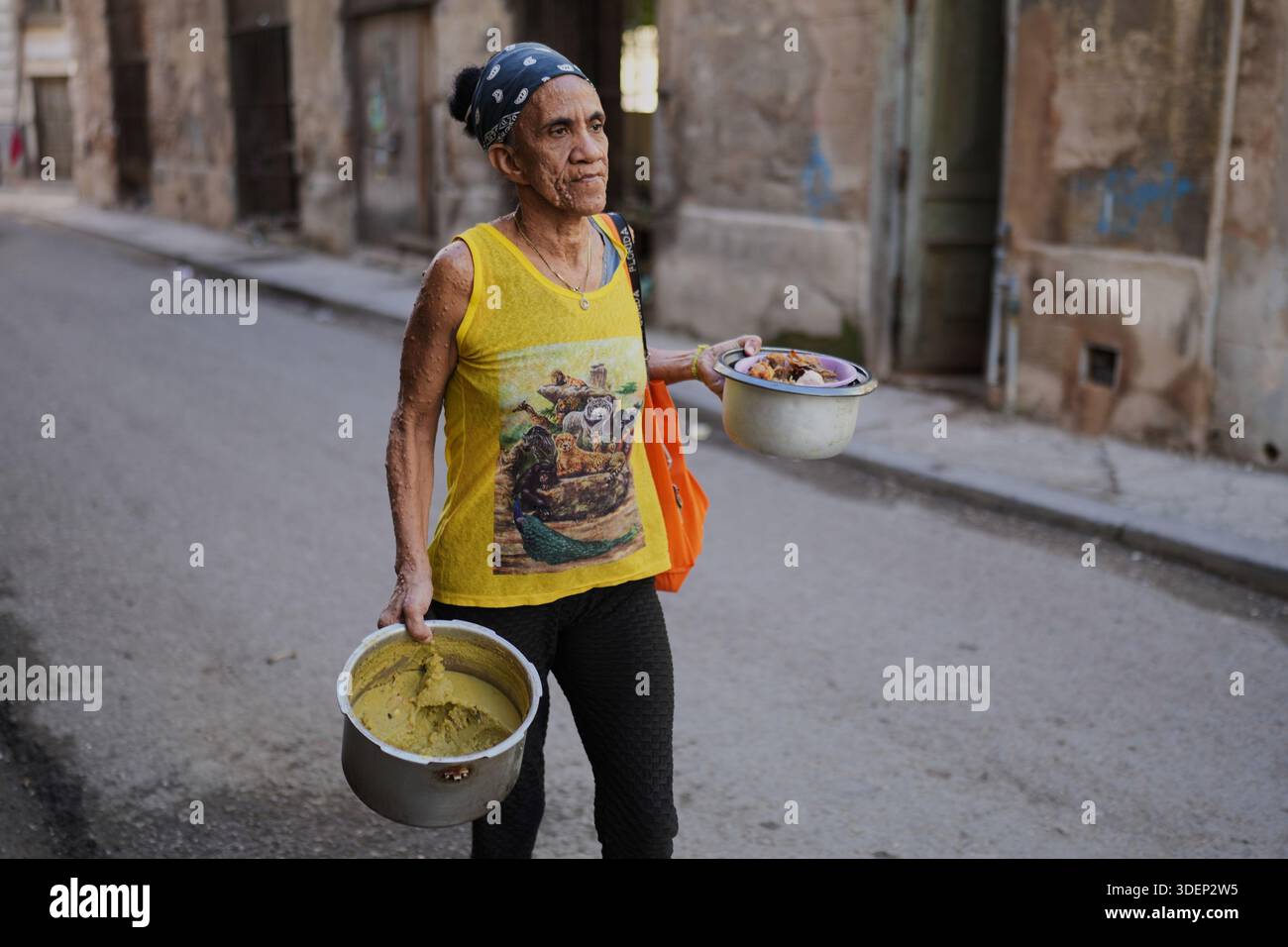 A woman carries pots of cooked food in Havana, Cuba, Thursday, Jan. 8 ...