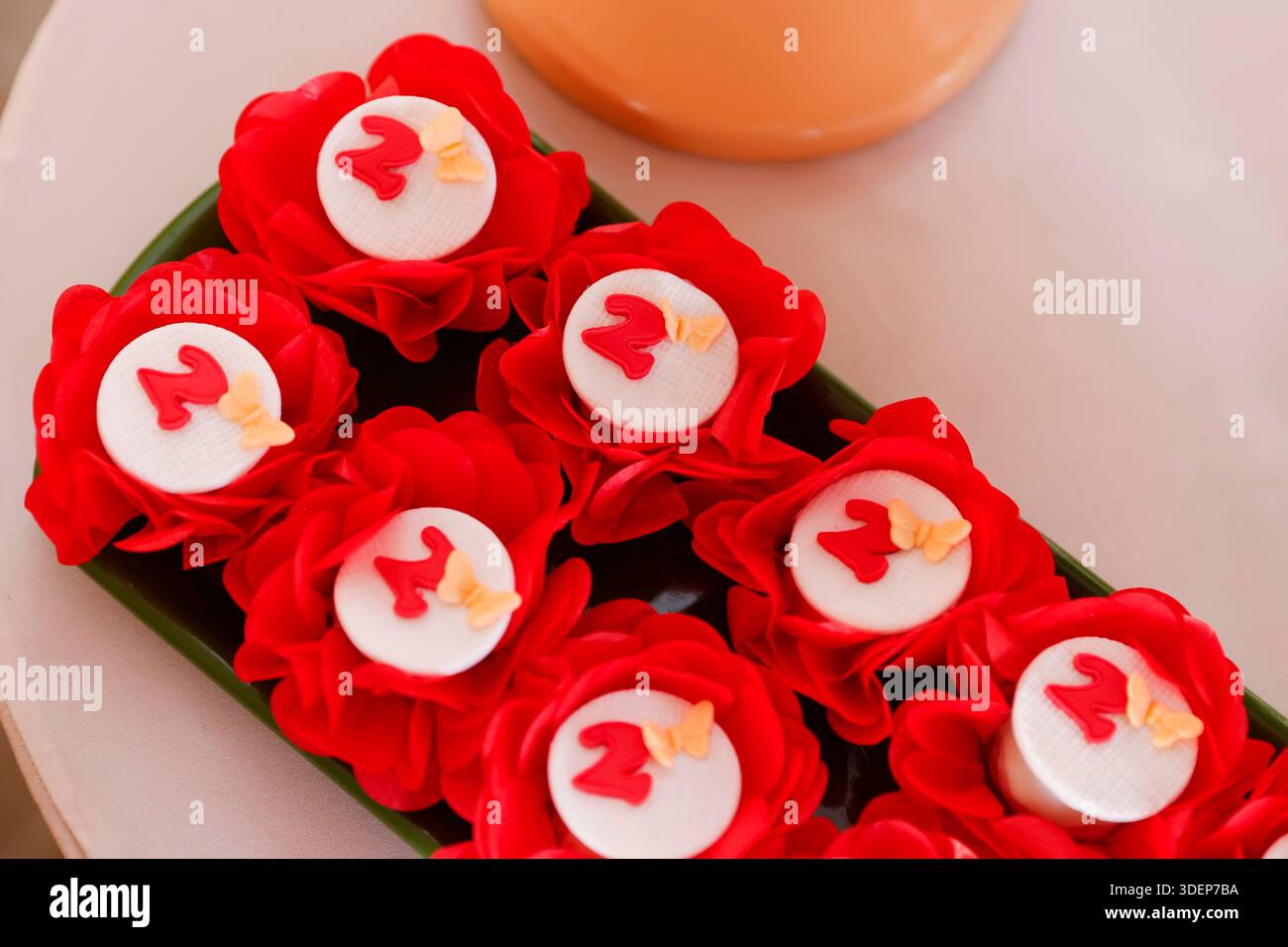 Party sweets in red flower-shaped paper liners, topped with white glaze ...